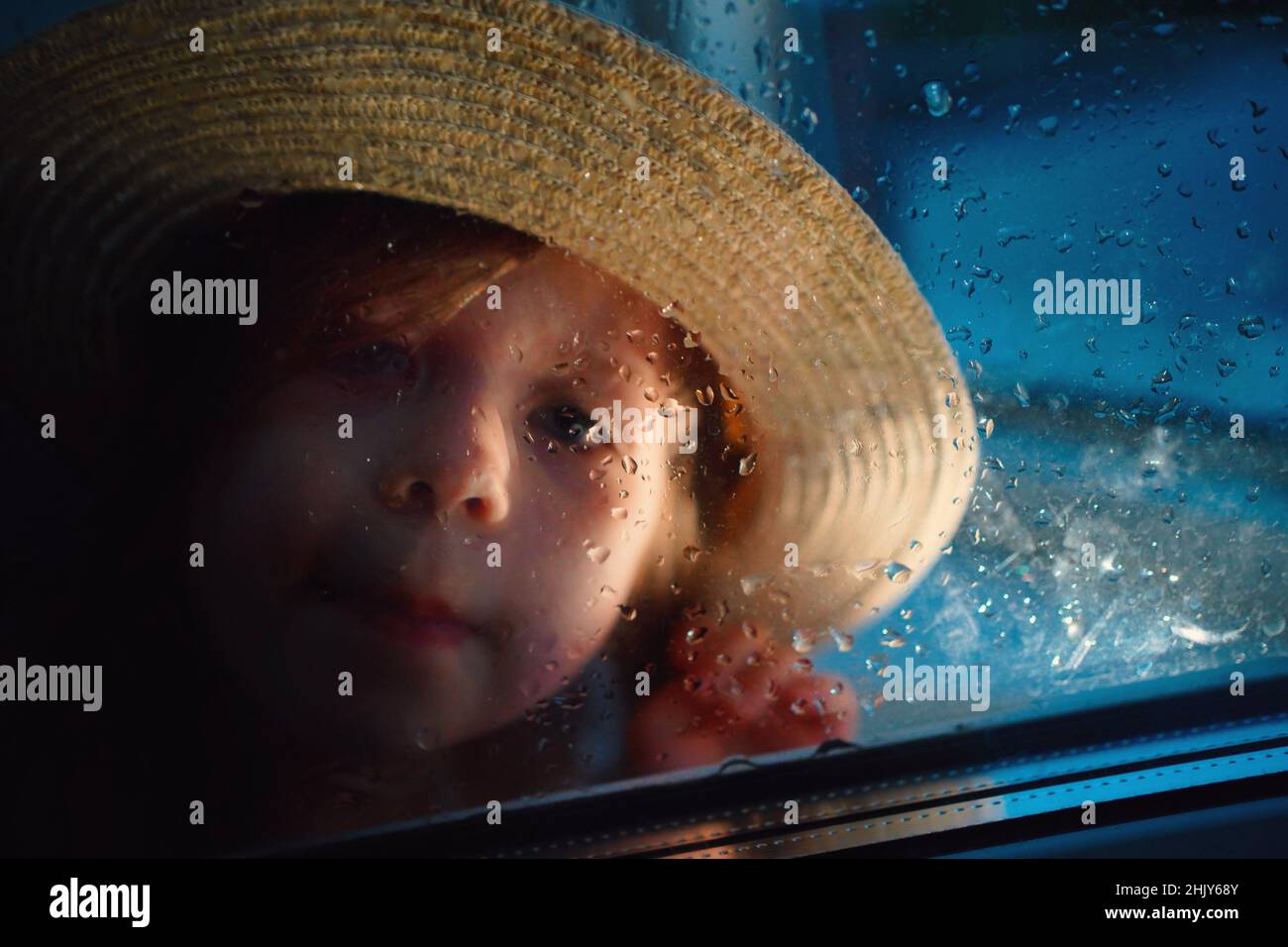 a girl in a straw hat, rain outside the window Stock Photo - Alamy