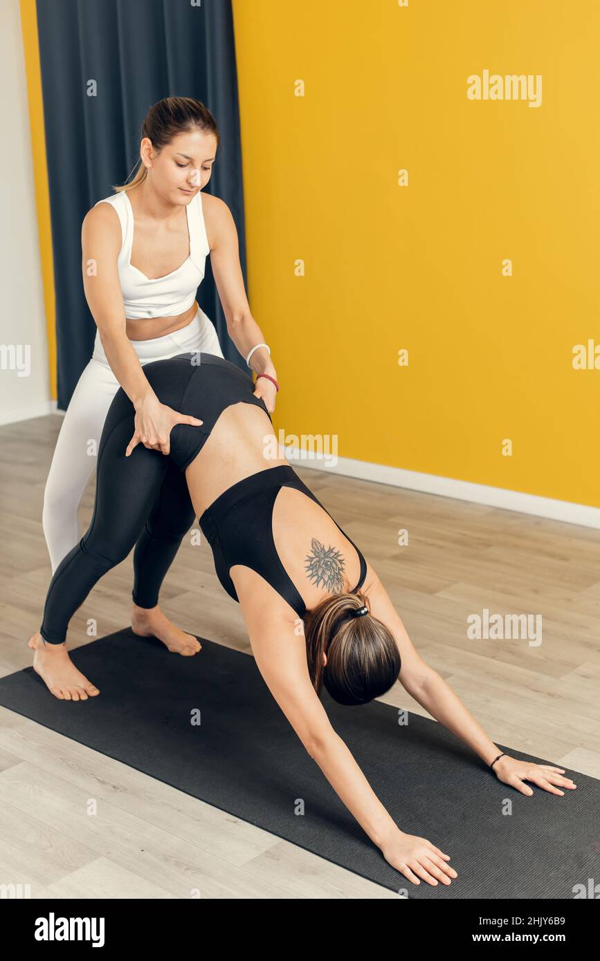 A female yoga coach controls the performance of a pose, asana ...