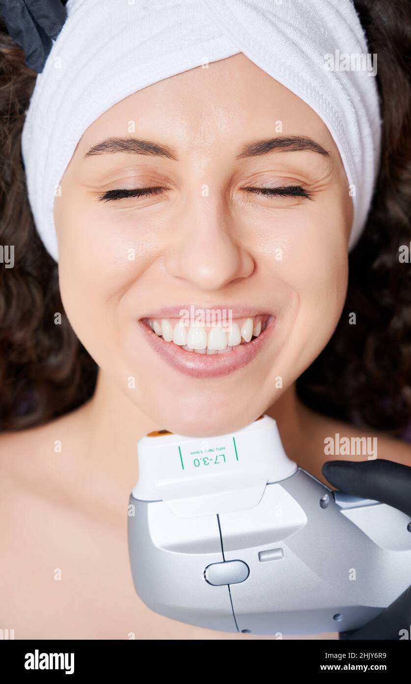 Closeup view of smiling woman's face receiving face lifting by non ...