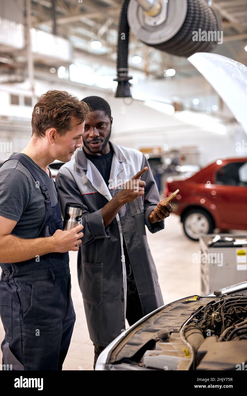 american and black Men mechanic inspection checking bug in engine from ...