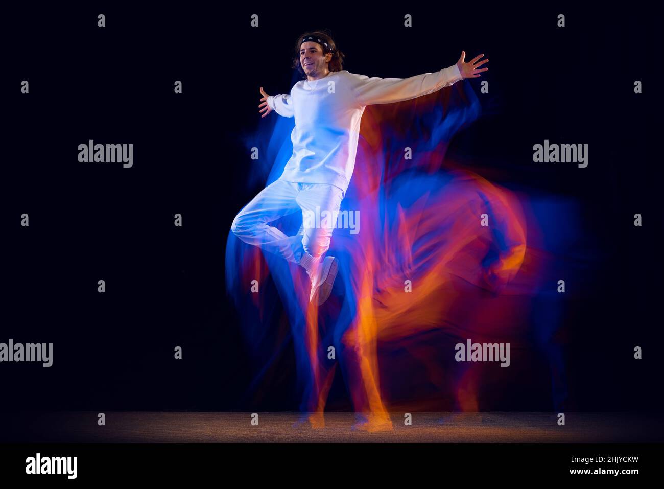 Flexible man in sports white suit dancing hip-hop isolated on dark ...