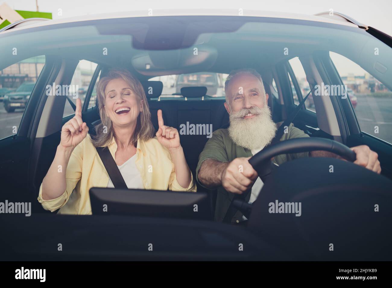 Photo of lovely senior married couple have fun listen music ride car ...