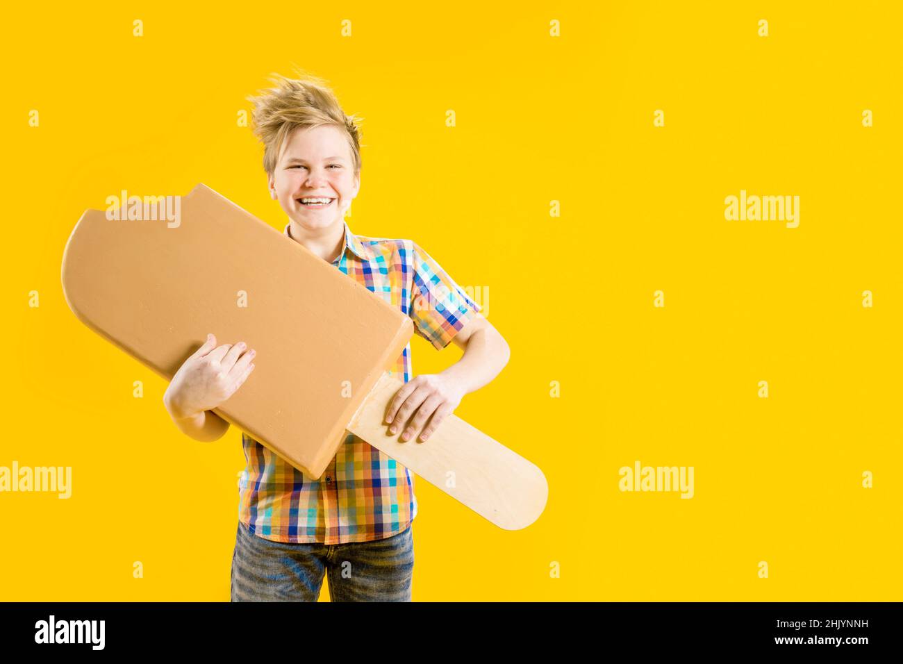 A cute boy is holding a huge ice cream on a stick in his hands ...