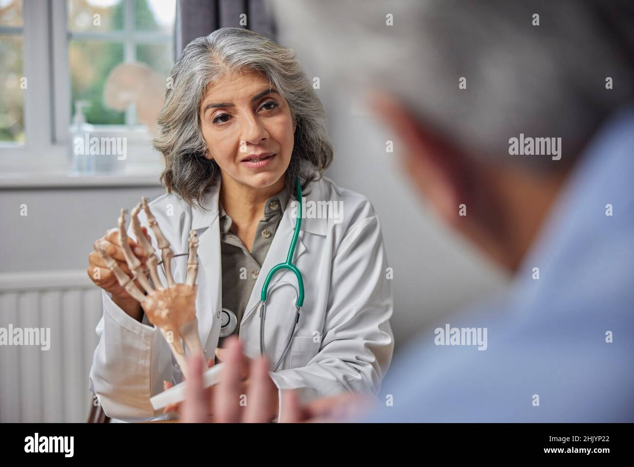 Mature Female Doctor Meeting With Male Patient Discussing Joint Pain In ...