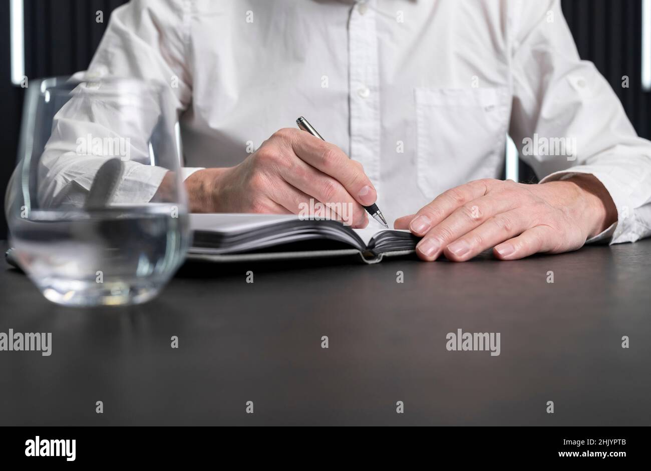 Man hands taking notes in planner. Employee sitting at desk and writing ...