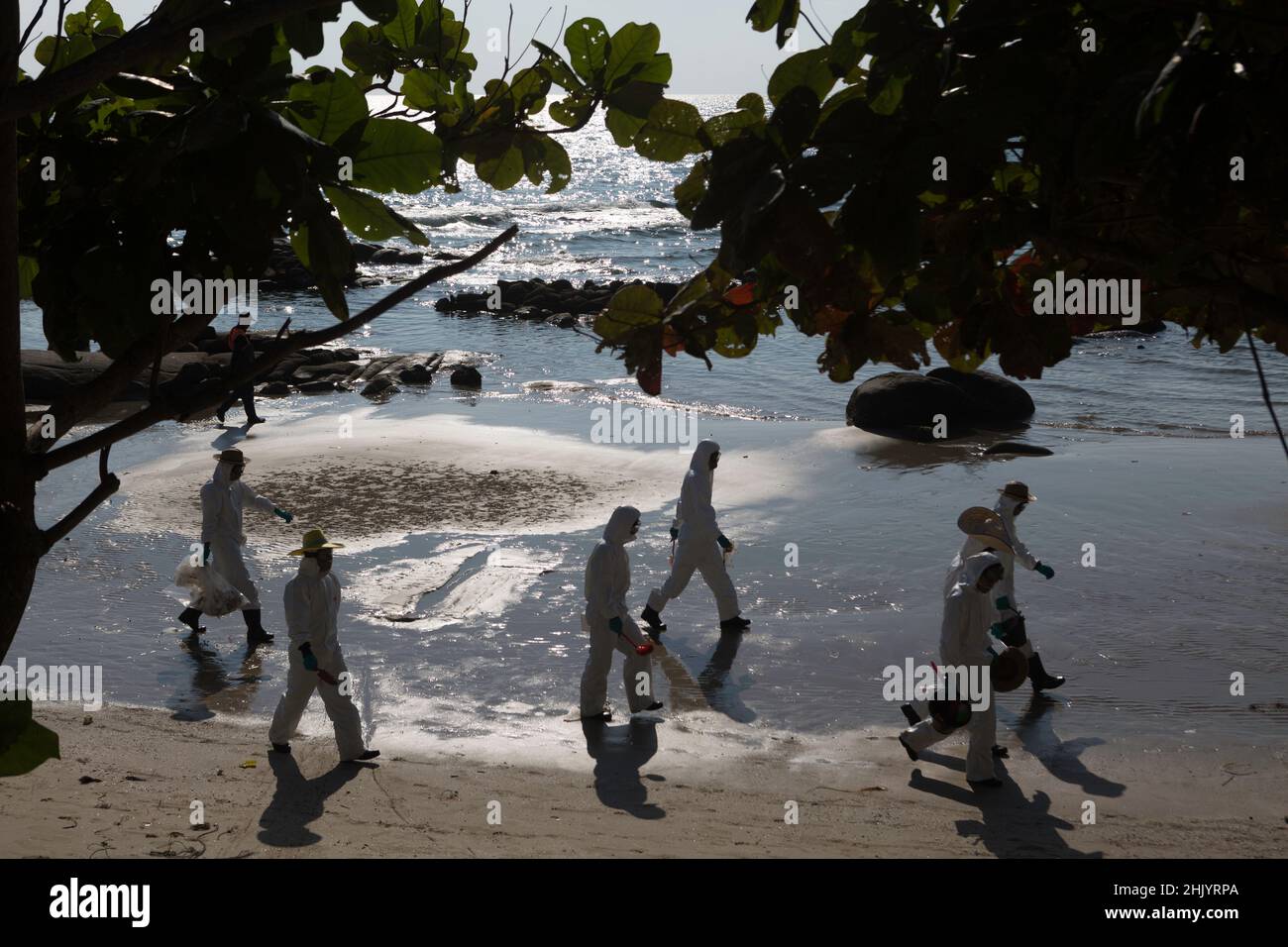 Workers cleaning up oil spills on the beach are walking back to the ...