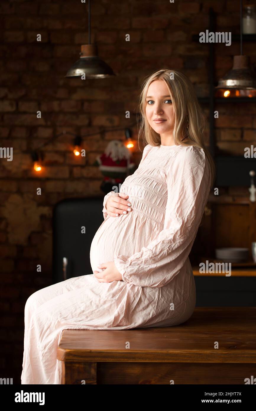 Pregnant woman sitting in the kitchen on the table Stock Photo - Alamy