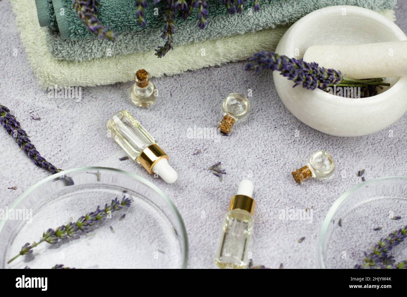 Composition of bottles with lavender oil, lavender flowers, mortar and pestle and petri dishes ...