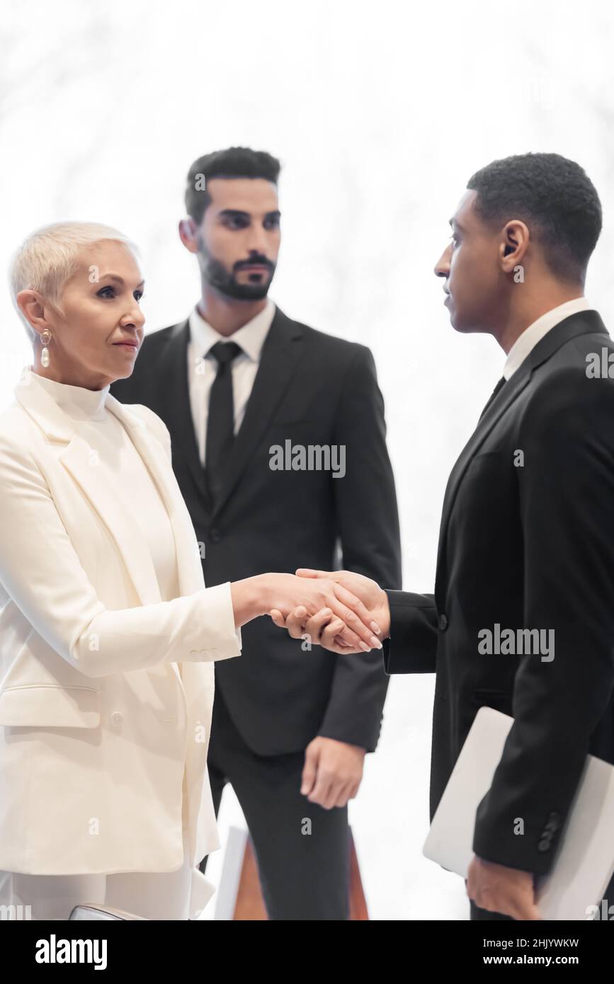 stylish senior businesswoman shaking hands with african american ...