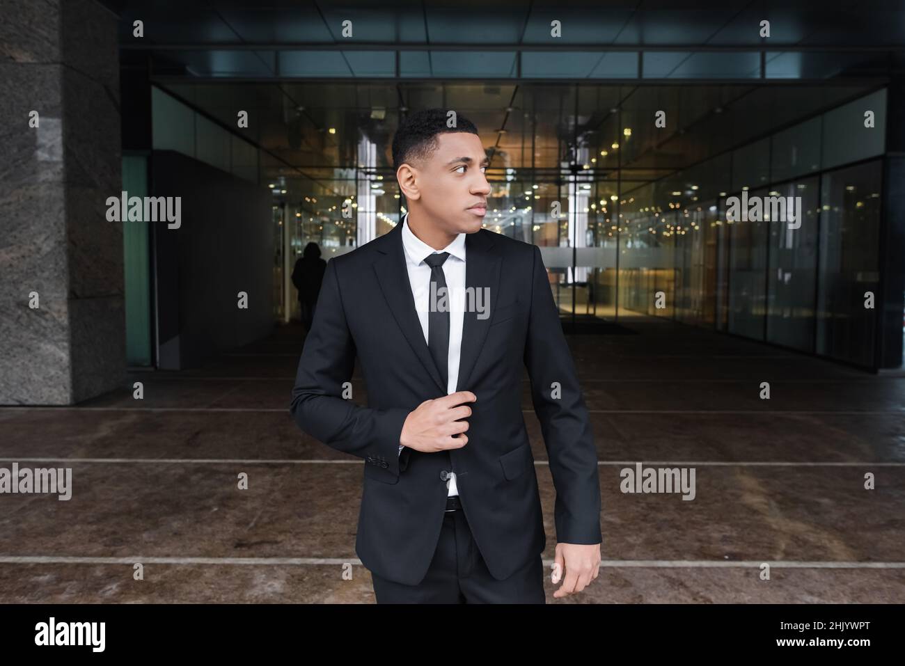 african american security man in formal wear looking away near entrance ...