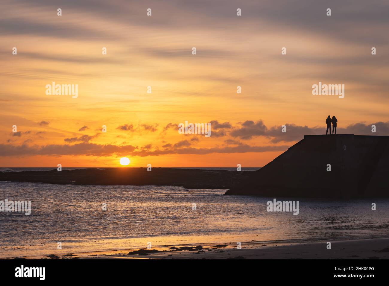 Two people watching the sunrise at Cullercoats Stock Photo - Alamy