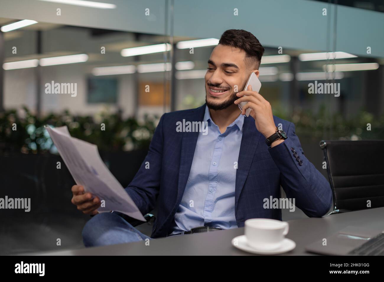 Happy arab manager reading documents and having phone conversation ...