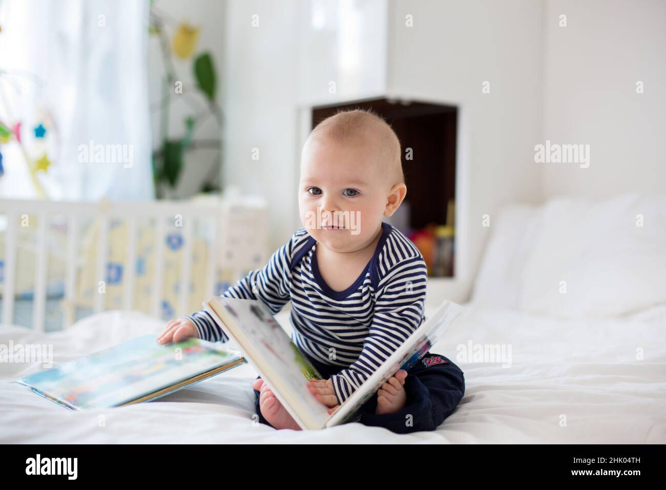 Portrait of a cute smiling infant baby boy reading a book. Happy ...