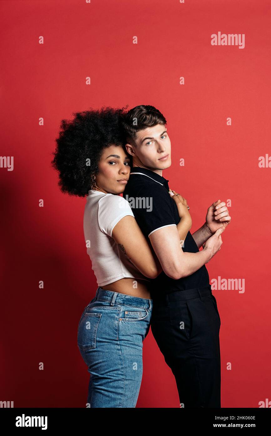 Multiracial couple studio shooting over a red background Stock Photo ...