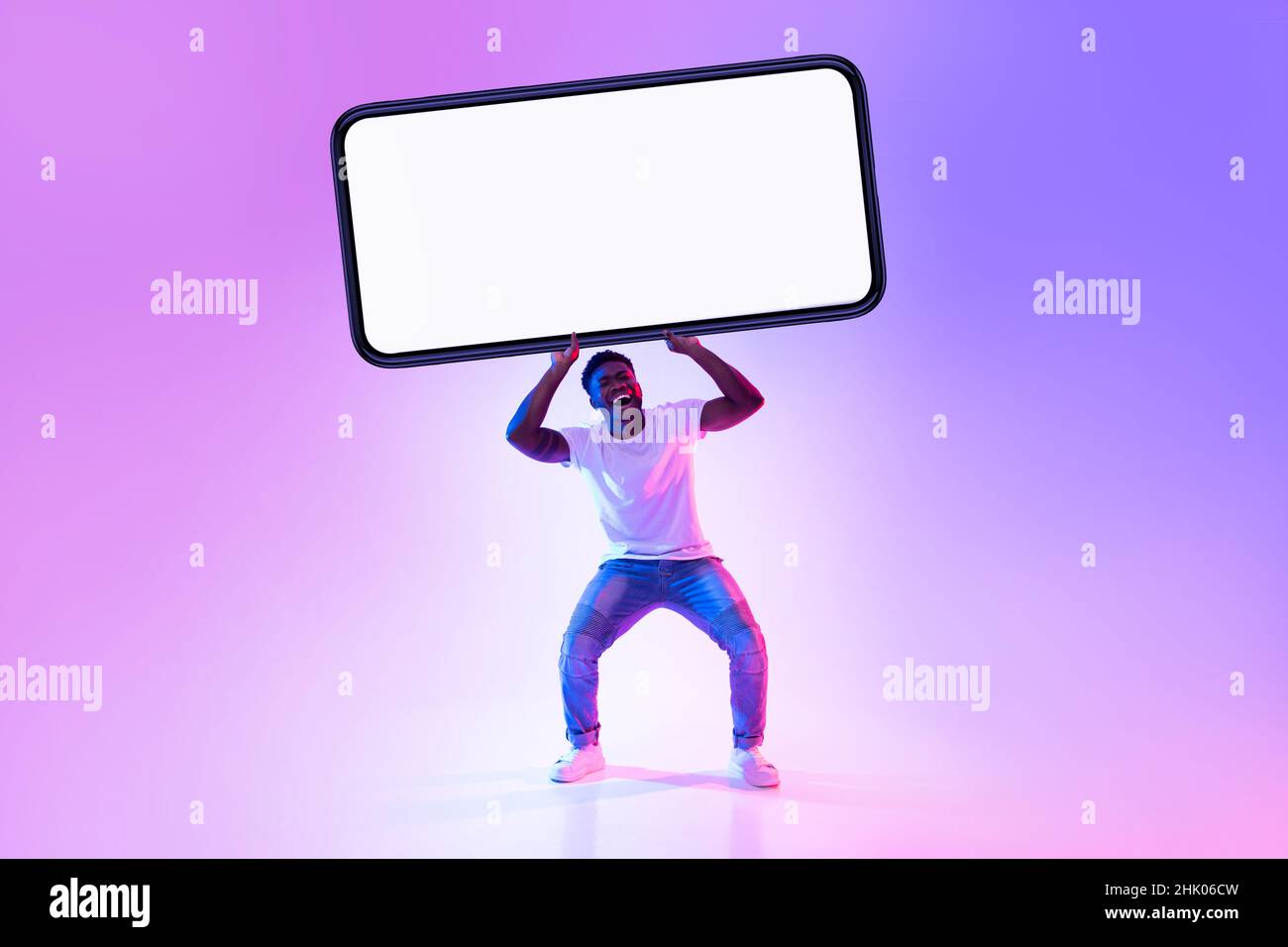 Handsome young black man holding huge heavy smartphone with empty white ...