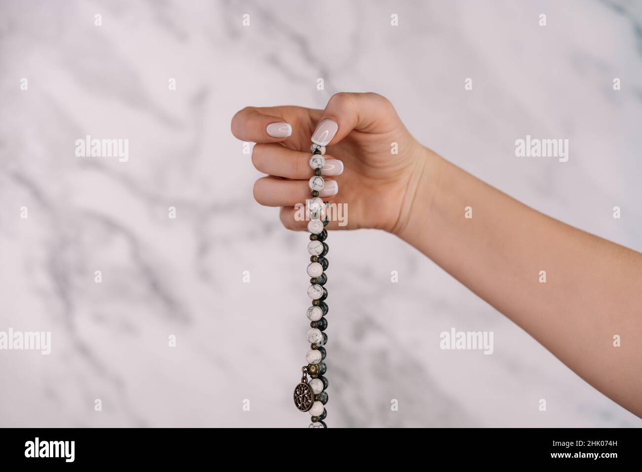 Woman lit hand counts mala beads strands of gemstones used for keeping ...