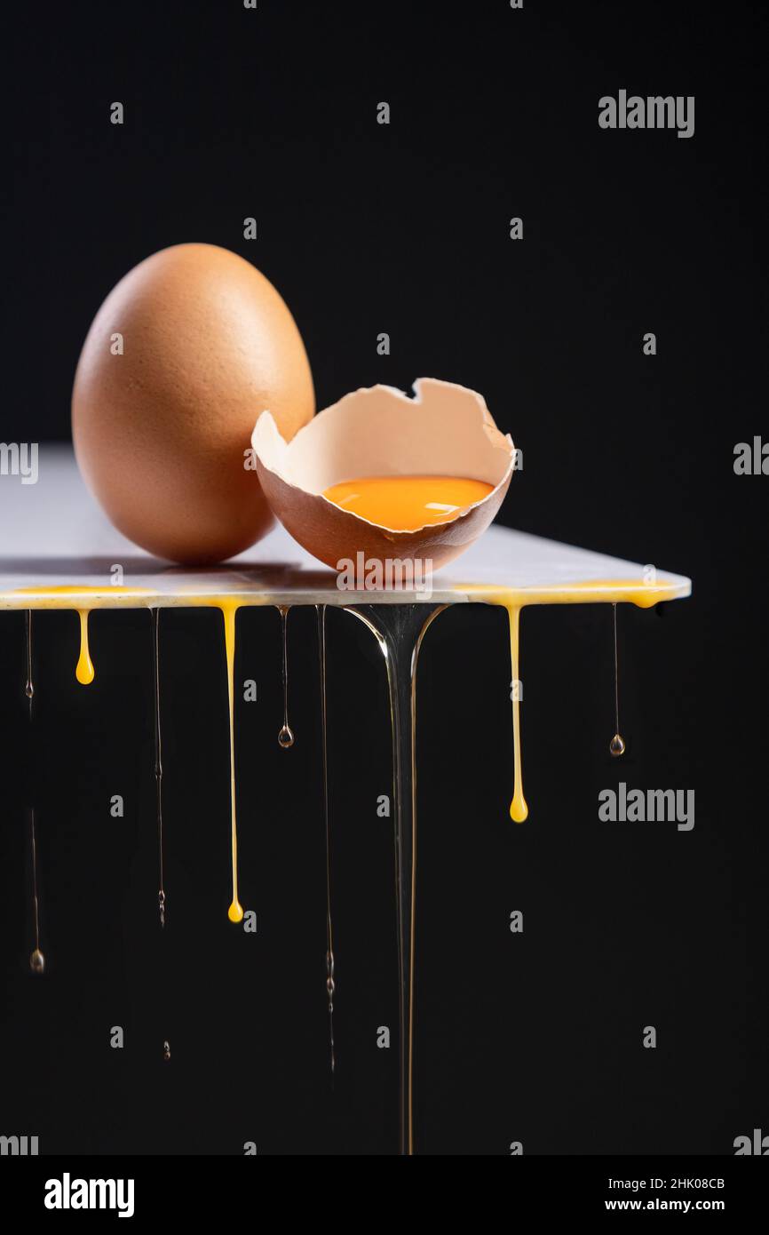 Fresh egg spilling out on black background Stock Photo - Alamy
