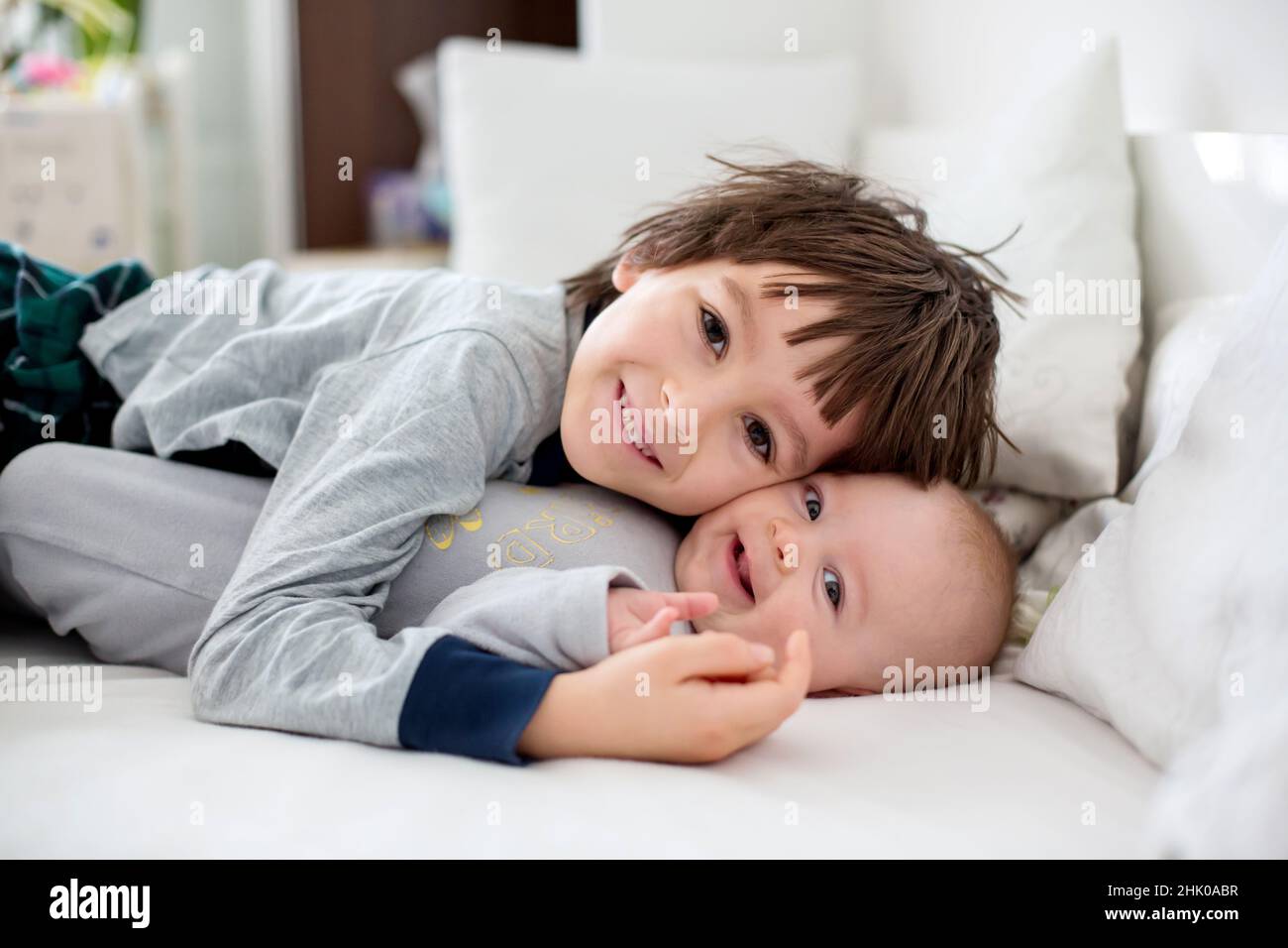Two children, baby and his older brother in bed in the morning, playing ...