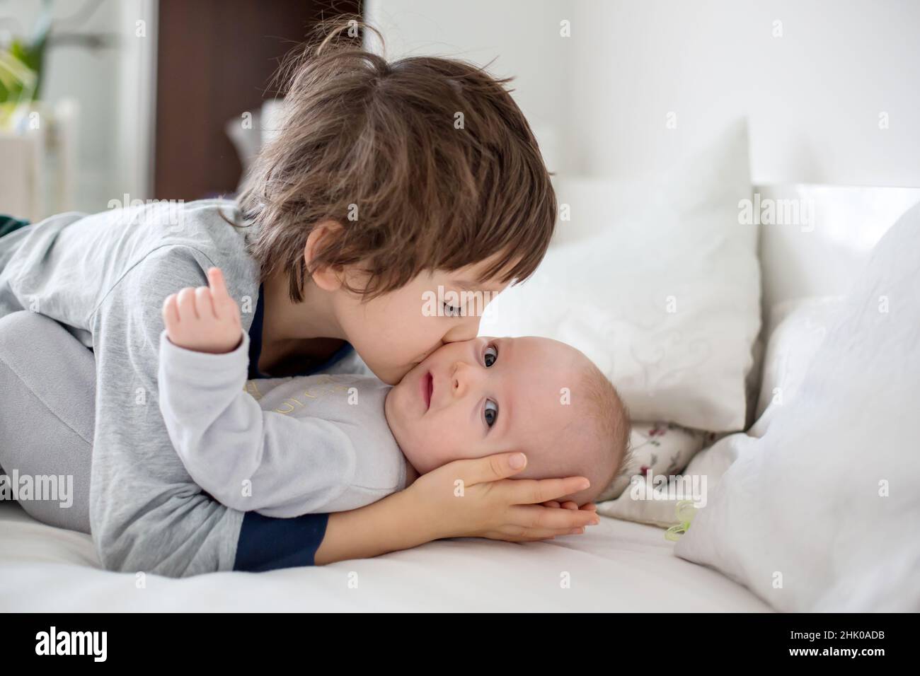 Two children, baby and his older brother in bed in the morning, playing ...