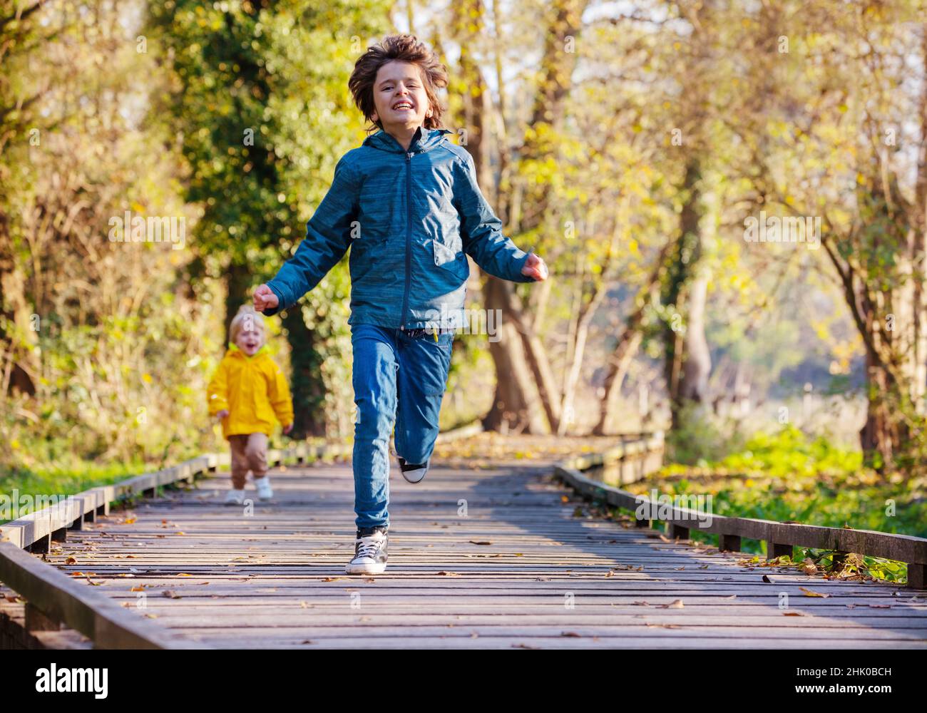 Happy teen running from his little brother in park Stock Photo - Alamy
