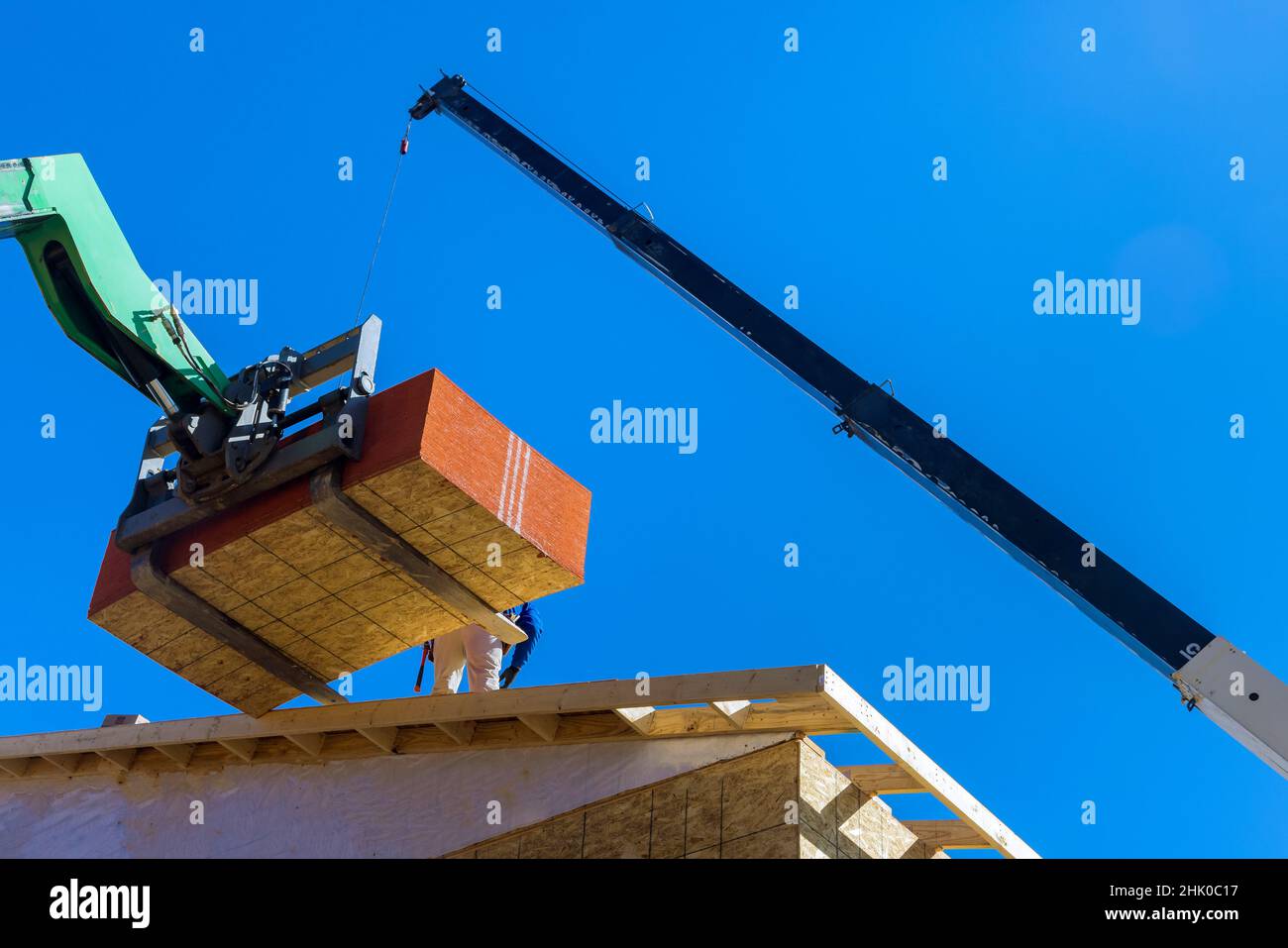 Builders are working on the roof covering it with plywood layer using ...