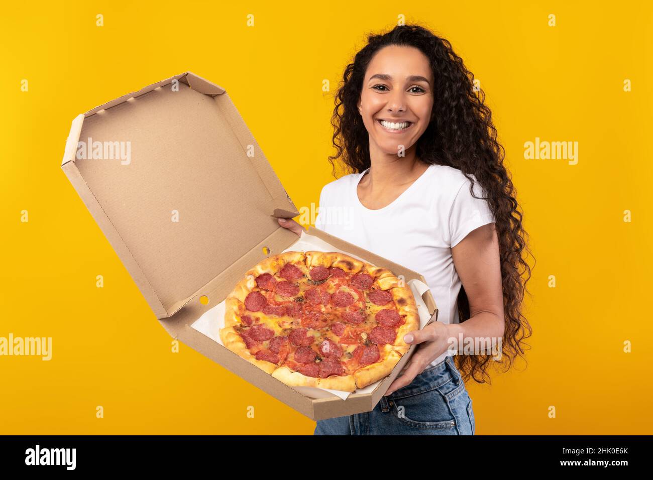 Happy Latin Lady Holding Pizza Offering To Camera Stock Photo - Alamy