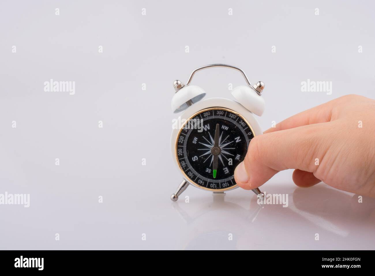 Child holding a compass on the alarm clock Stock Photo - Alamy
