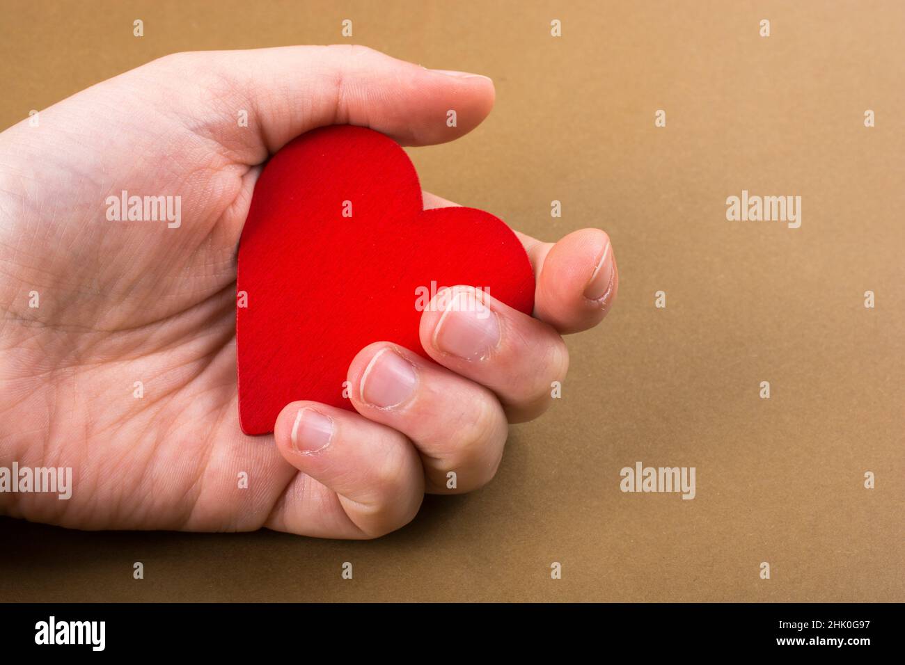 Red color heart shaped object in hand on dotted paper Stock Photo - Alamy