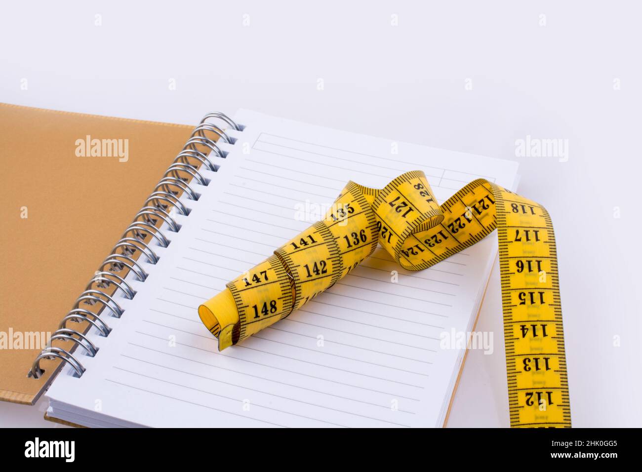 Measuring tape near a notebook on a white background Stock Photo - Alamy