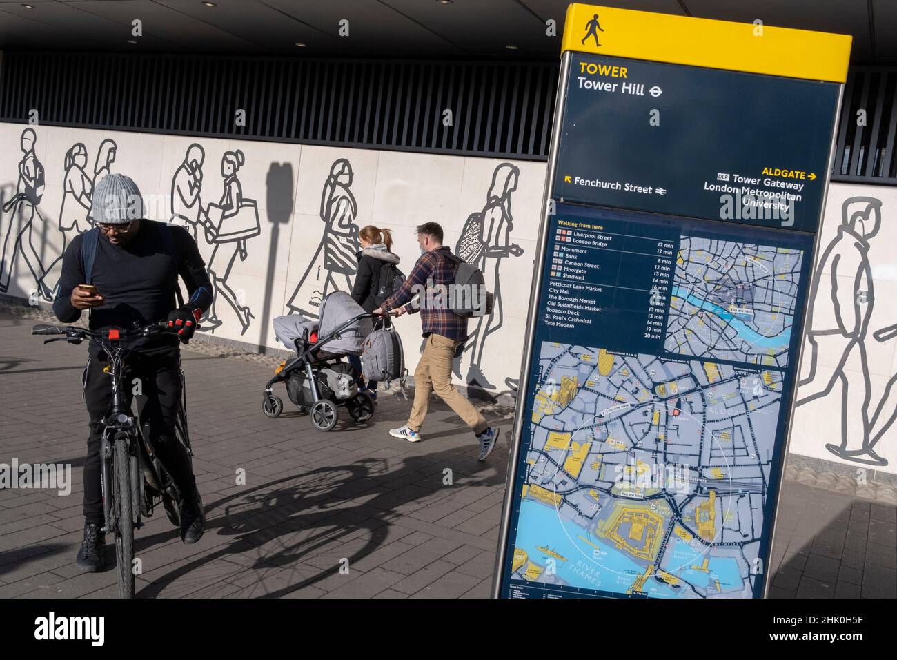 A cyclist and pasing Londoners next to a city map and a themed mural ...