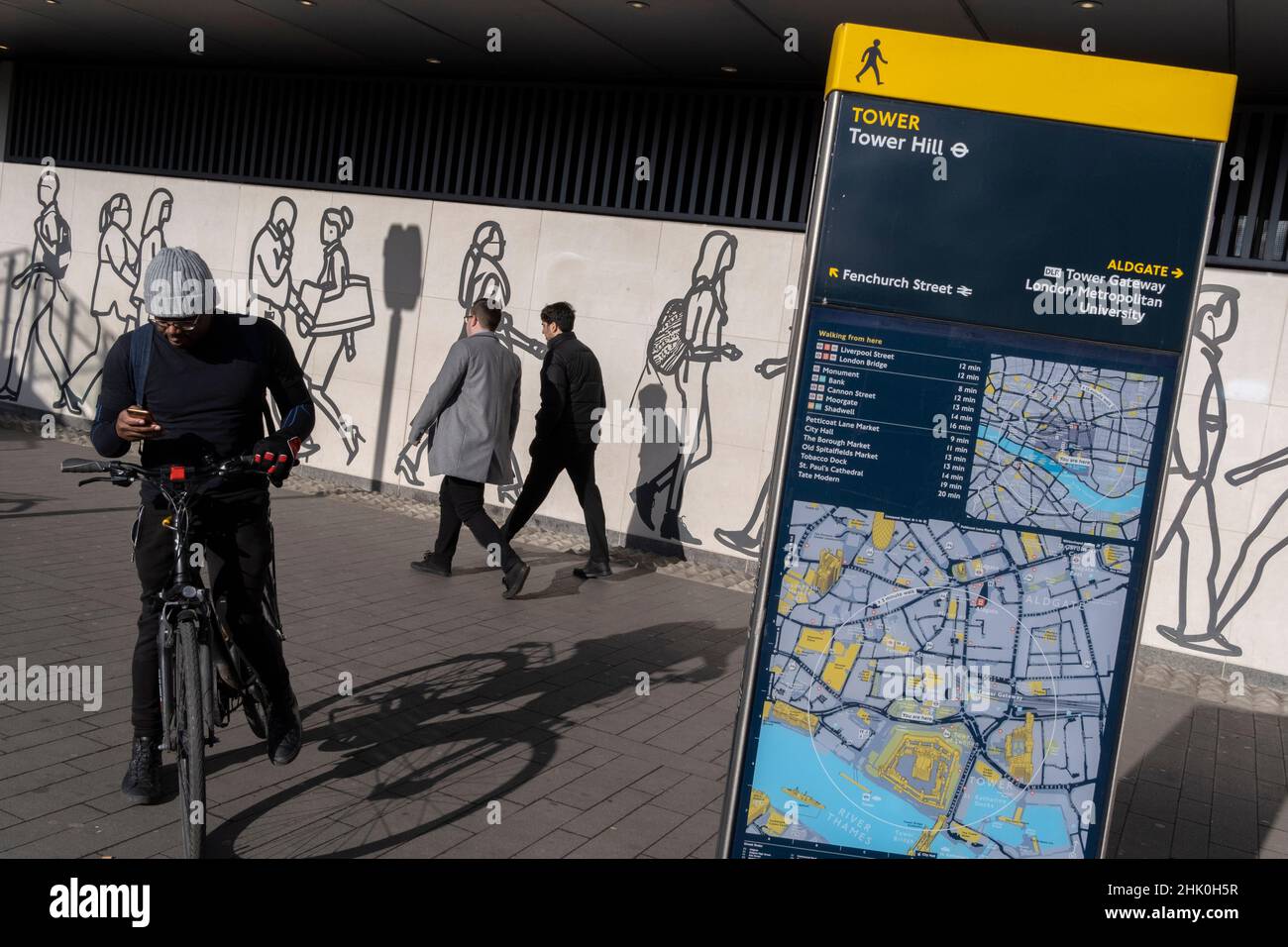 A cyclist and pasing Londoners next to a city map and a themed mural ...