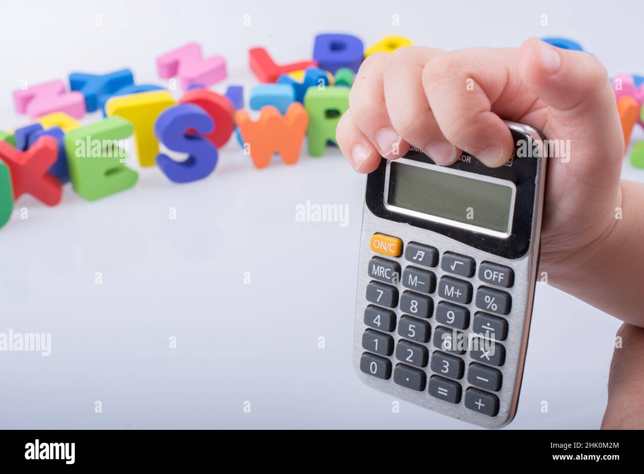 Little calculator in hand with colorful letters behind on white Stock ...