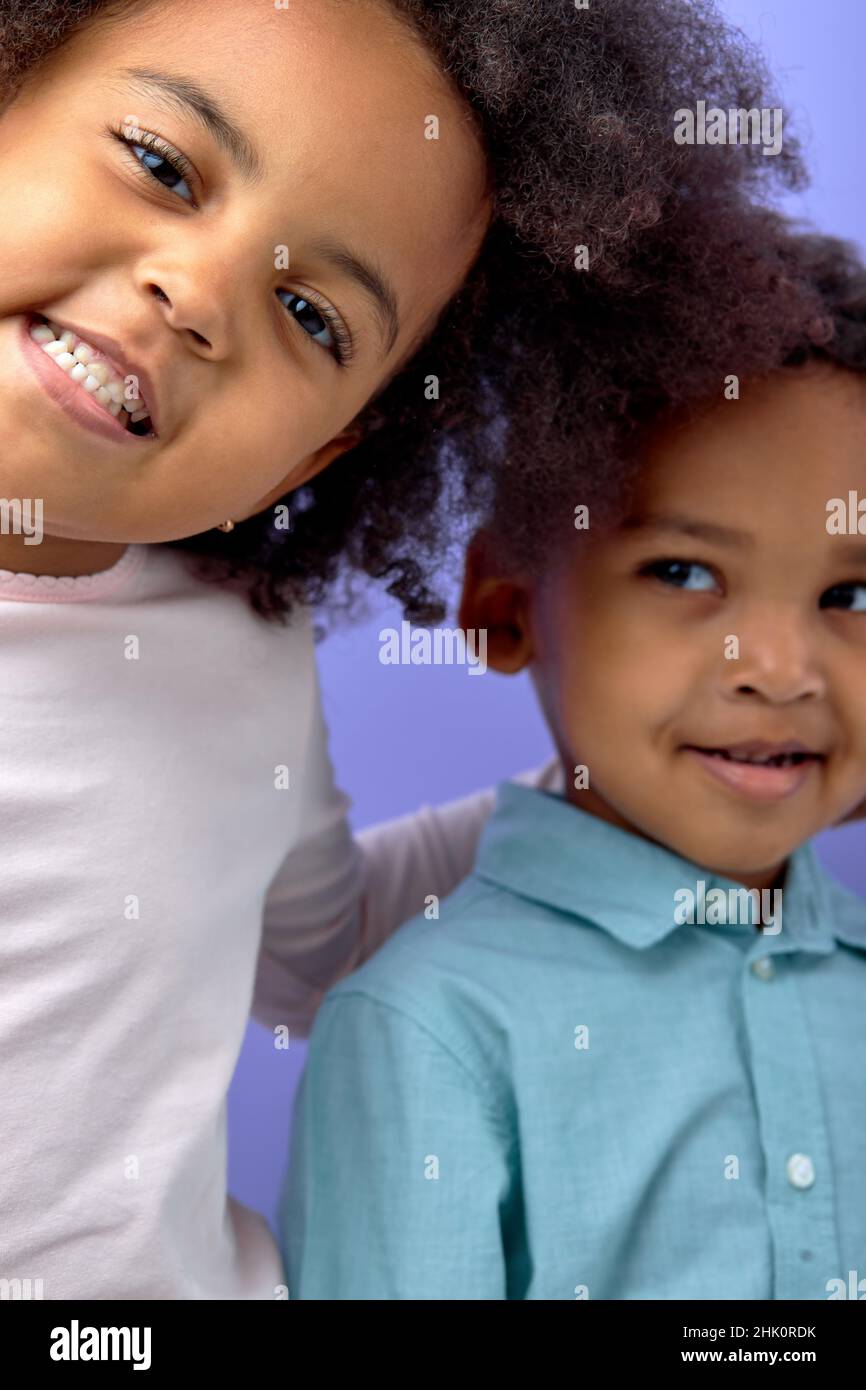 Two excited black children posing at camera and cheerfully smiling over ...