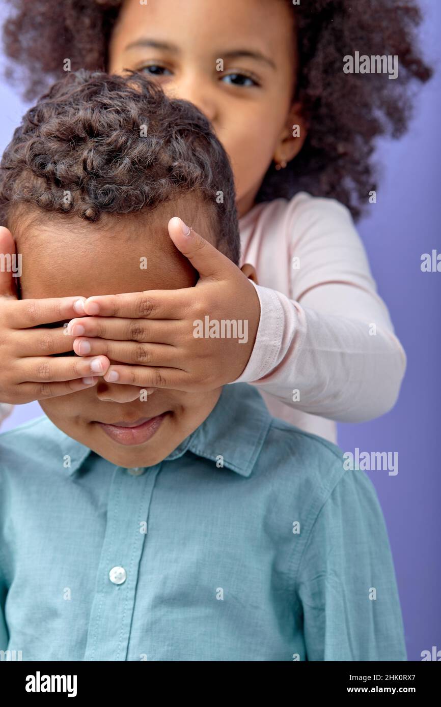 cheerful carefree little girl covering eye of boy with arms, sincerely ...