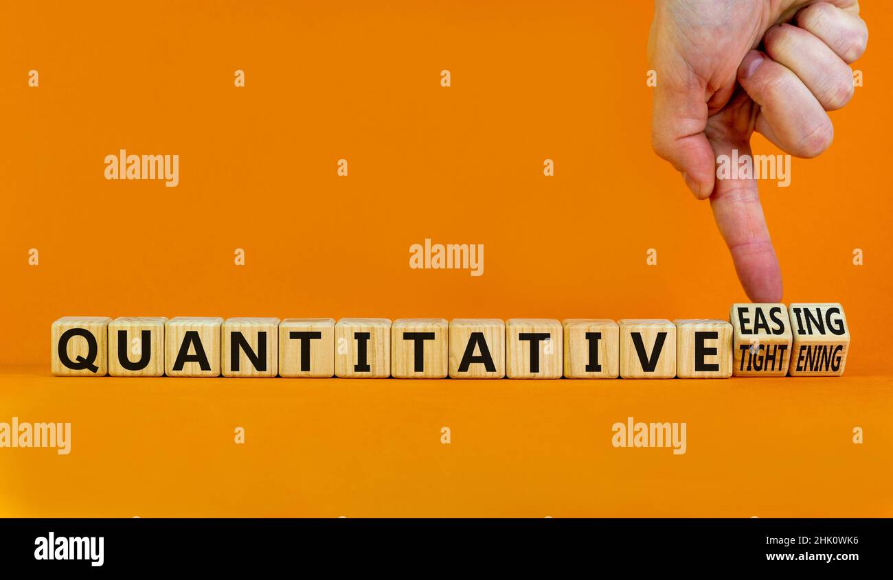Quantitative easing or tightening symbol. Businessman turns cubes ... Quantitative easing or tightening symbol. Businessman turns cubes ...