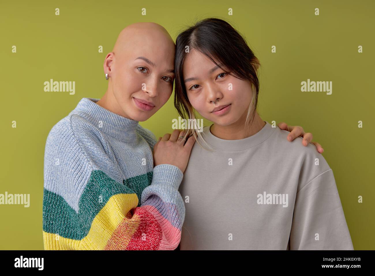 Diverse women posing at camera supporting each other, asian and another ...