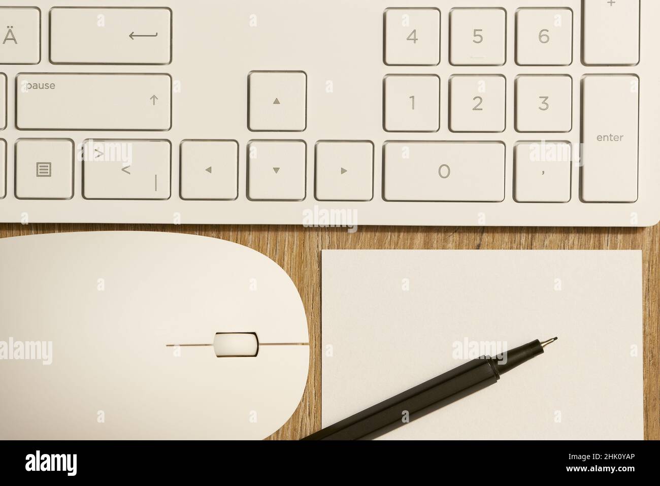 Keyboard from a computer and a computer mouse and pen and paper on a ...
