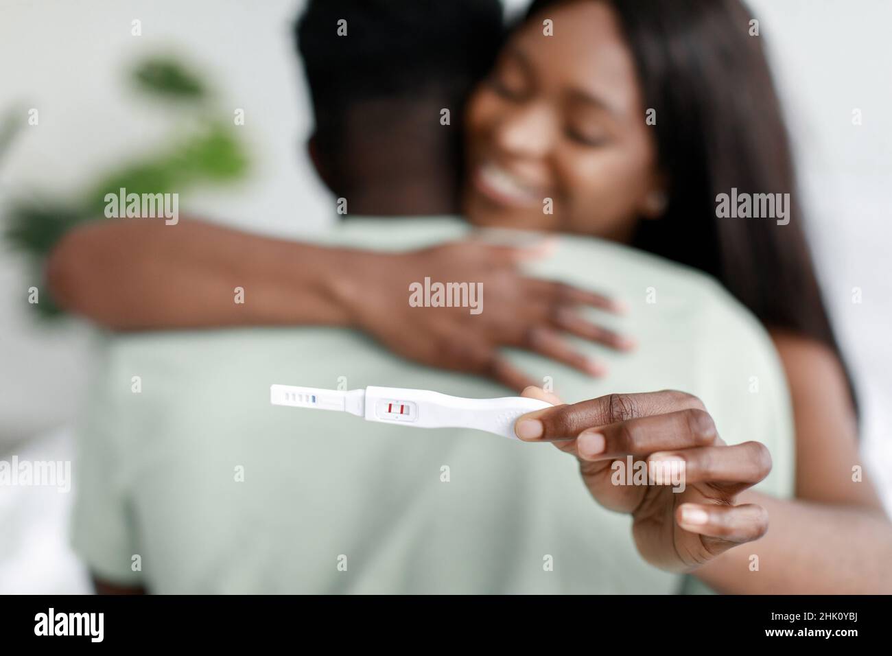 Glad Smiling Millennial Black Woman Hugging Man Show Pregnancy Test At