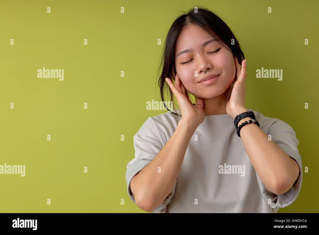 happy chinese woman listening to music in headphones, looking relaxed ...