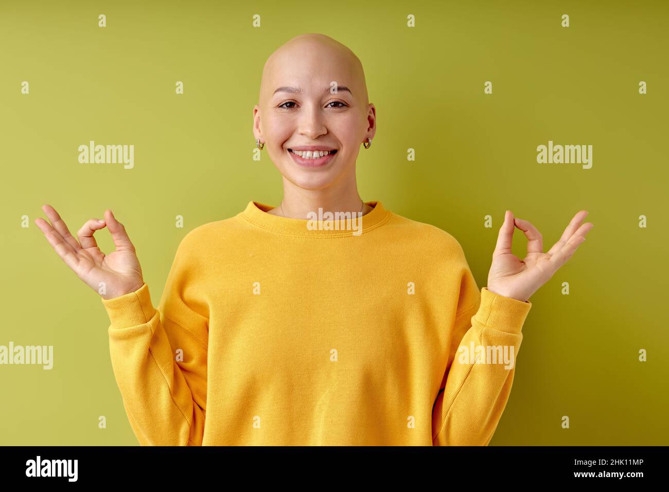 Keep calm, yoga. Happy young caucasian bald woman isolated on green ...