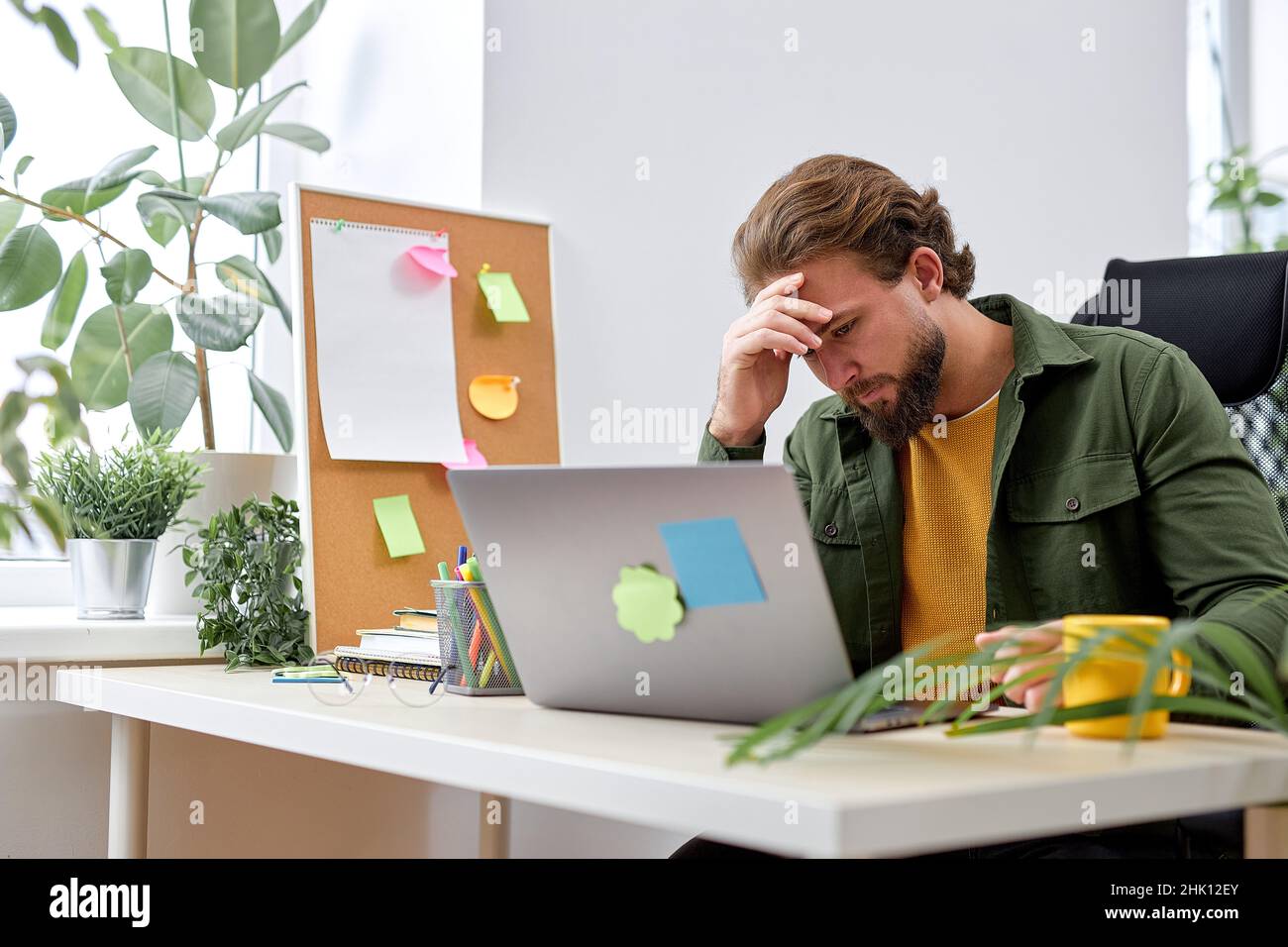 Tired guy sit working on laptop in modern office having deadlines, hard ...