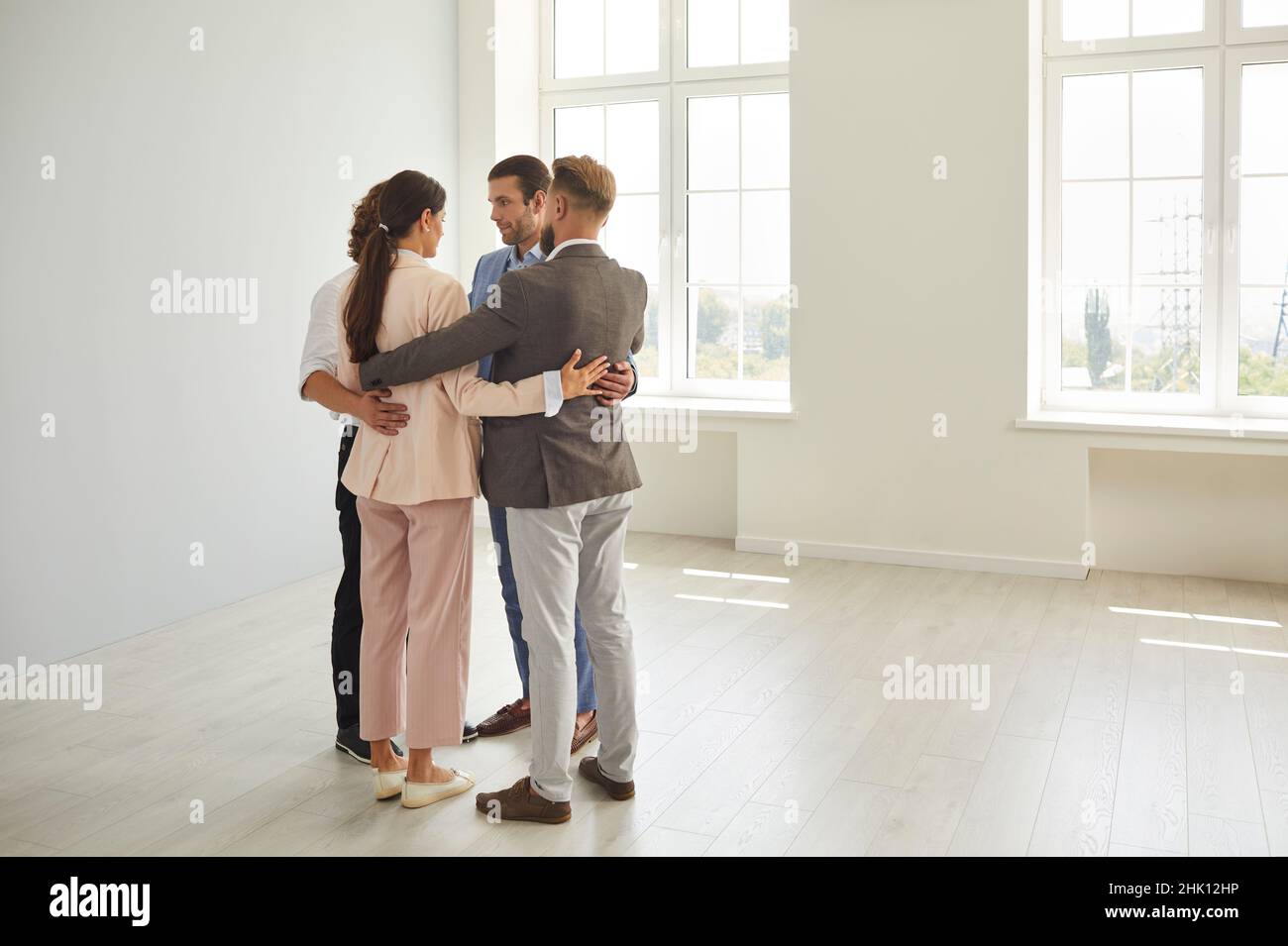 Team of supportive business colleagues standing in a circle and hugging ...