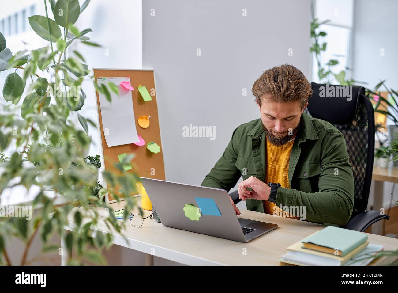 bearded male in casual wear checking time before going home, sitting ...