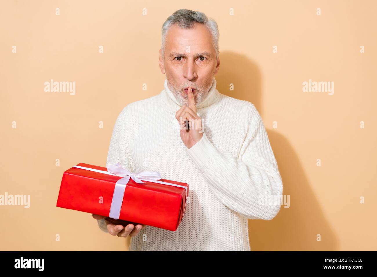 Portrait of attractive mysterious grey-haired man holding gift new year ...