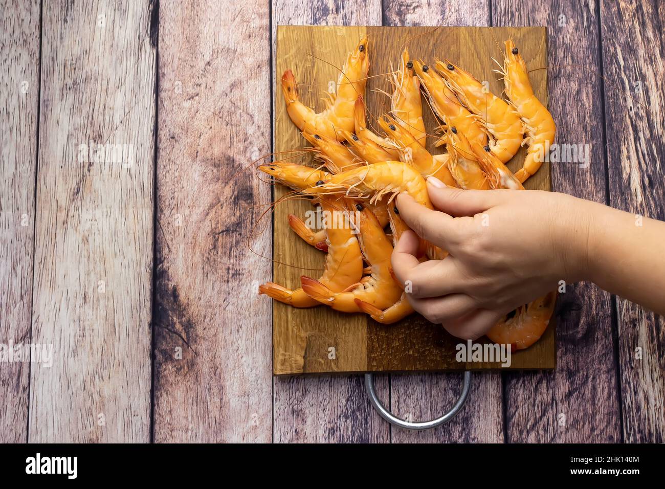 a hand with two fingers holds a shrimp against the background of a ...