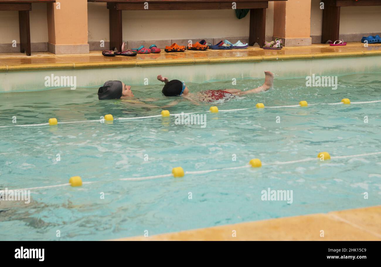 Female swimming instructor teaching a young boy to swim in a ...