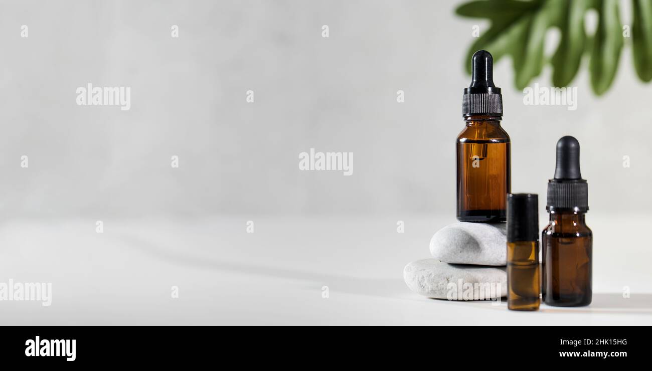 Glass droppers with cosmetic products on a pedestal made of stones on a ...