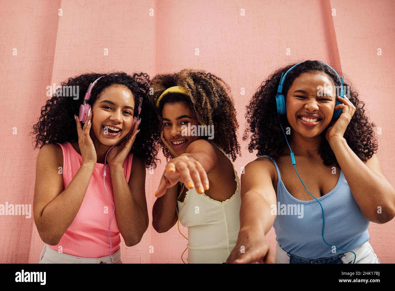 Three laughing women with curly hair dancing together and looking at ...