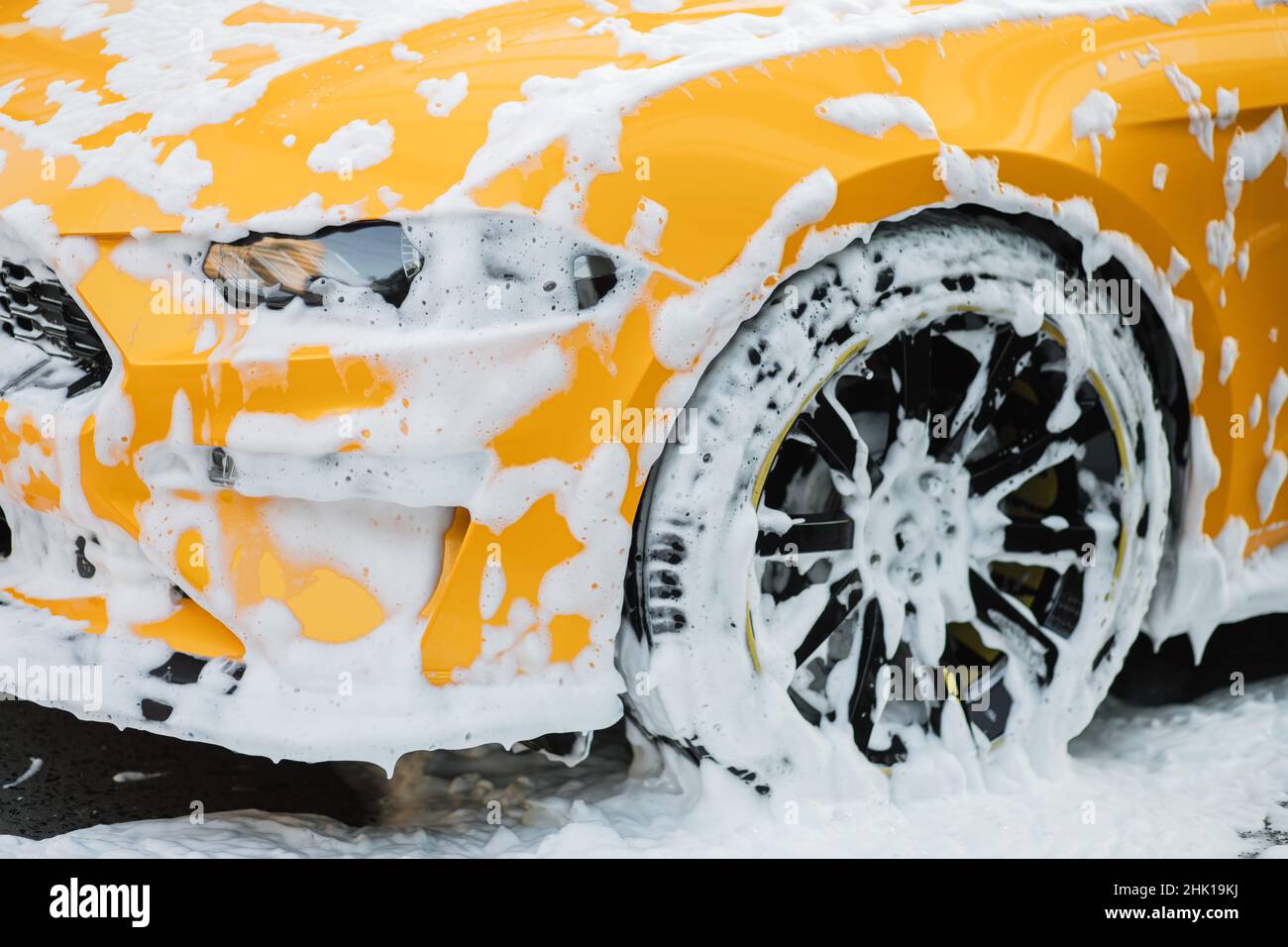 Cropped image of wheel of luxury yellow car in outdoors self service ...