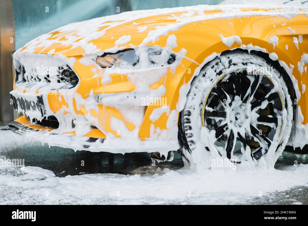 Cropped image of wheel of luxury yellow car in outdoors self-service ...
